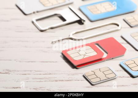 Different SIM cards, ejector and tray on wooden background, flat lay ...