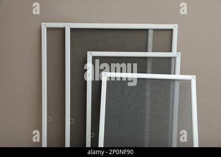 Set of window screens near beige wall Stock Photo - Alamy