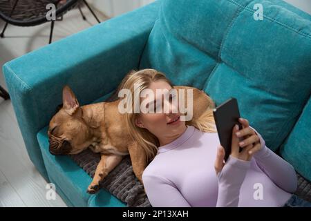 Female whiling away time with her dog on sofa Stock Photo - Alamy