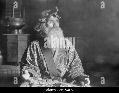 Ainu chief wearing a headdress seated with a sword in his lap, 1908 ...