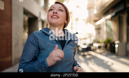 Young redhead woman wearing sportswear standing with relaxed expression ...