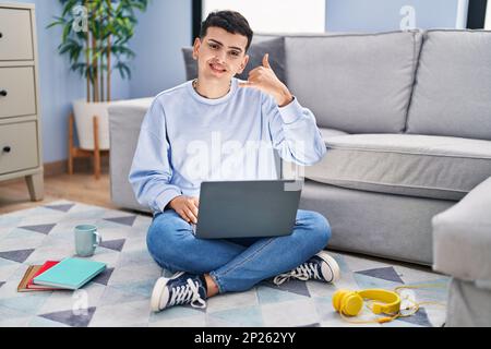 Non binary person studying using computer laptop sitting on the floor ...
