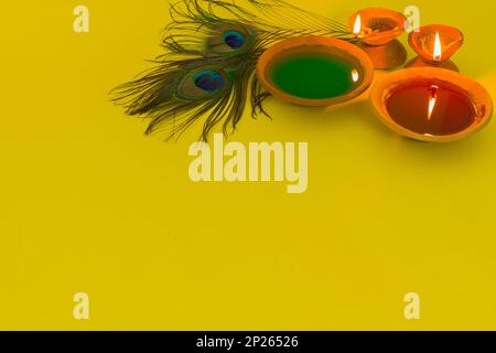 happy holi celebration with colors, clay lamp and peacock feather ...