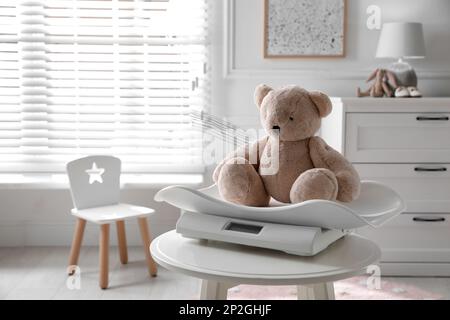 Baby scales with teddy bear on table in room Stock Photo - Alamy