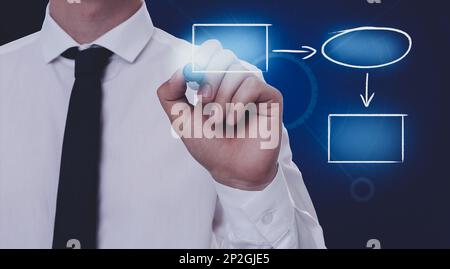 Man pointing at flowchart on virtual screen against black background ...