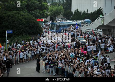A crowd of football fans watch the arrival of a bus carrying players of ...