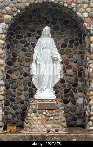 Statue of the Virgin Mary on a pedestal in front of water fountain wall ...