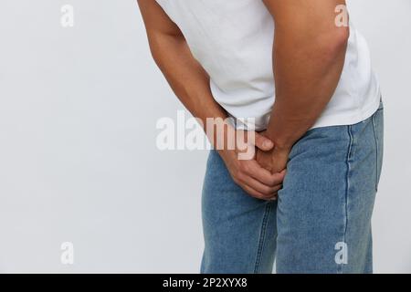 Man groin pain problems with potency and urination, urolithiasis, in white t-shirt on white ...