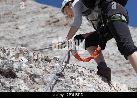 Climbing along a steel line on the via ferrata route in the dolomites ...
