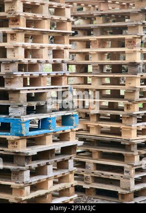Stack wooden pallets in huge empty industrial warehouse. White interior ...