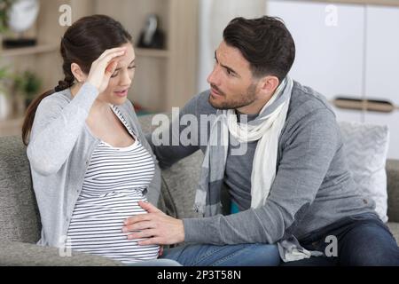 Sad pregnant woman fighting with her husband sitting on a sofa at home ...