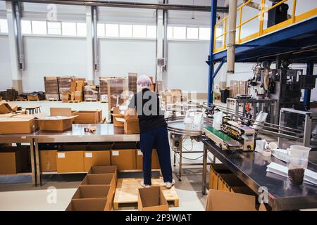 Worker packing coffee packages into cardboard boxes Stock Photo - Alamy