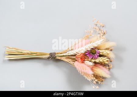 top view of tied bouquet of dried flowers and spikelets lies on light ...