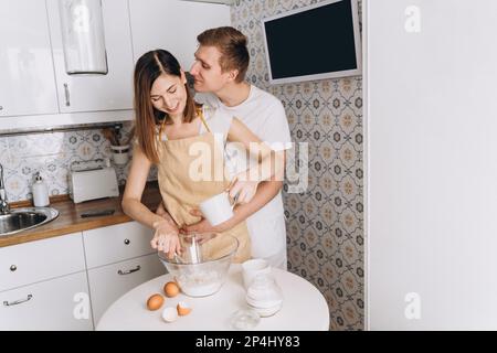 A loving couple cooks pancakes in the kitchen and hugs Stock Photo - Alamy