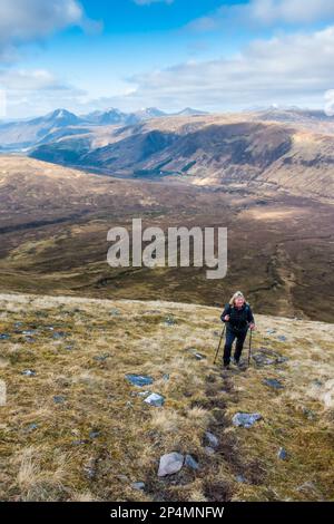 A walker on the steep boggy path up the scottish Munro mountain of ...