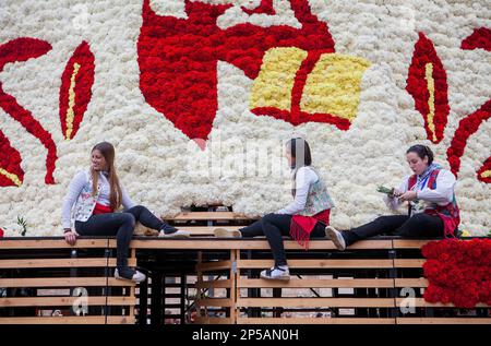 Woman placing flower offerings on large wooden replica statue of Virgen ...