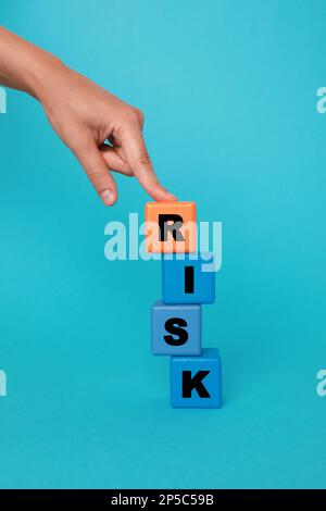 Woman making word Risk with colorful cubes on turquoise background ...