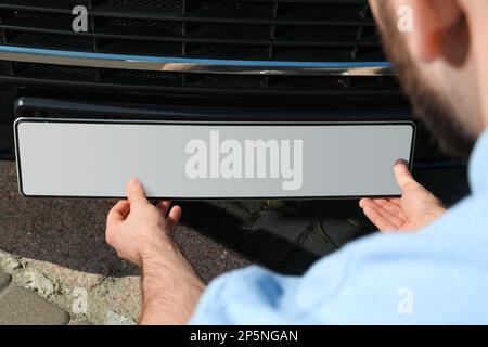 Man installing vehicle registration plate outdoors, closeup Stock Photo ...