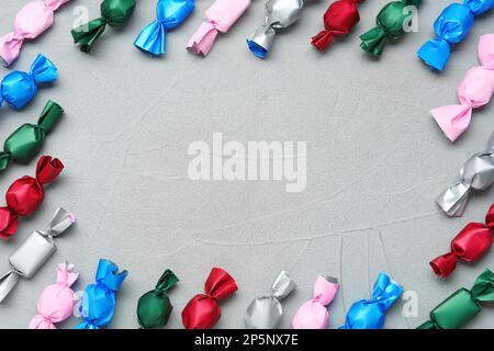 Frame of candies in colorful wrappers on light green background, flat ...