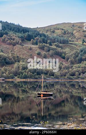 Sailing boat with reflection at anchor at Strontian, in Loch Sunart ...