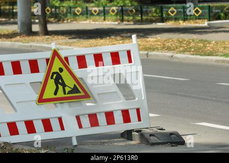Barricade with road construction sign on city street, space for text ...