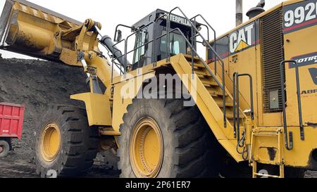 Wheel Loader loading soil on trucks, working at a huge mining site ...