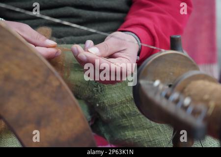 A street artist sewing manufacturing with traditional spinning wheel ...