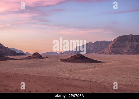 Wadi Rum plain at sunrise with soft light over the sand dunes and ...