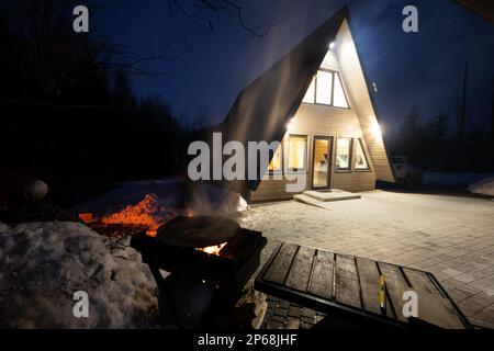 Wood fired barbecue against triangle country house at night Stock Photo ...