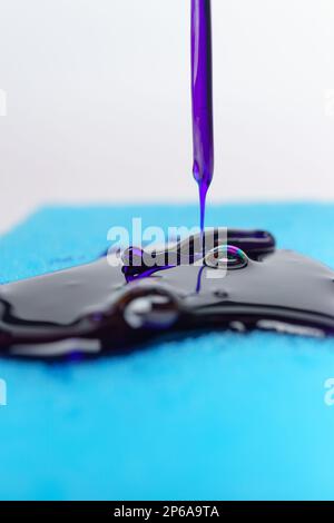 Purple liquid soap dripping on a blue sponge on a white background ...