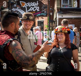A group of people at a steampunk festival. A man in a pith helmet has a ...