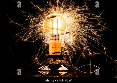 Isolated lighted up incandescent lamp with fire sparks and filament in ...