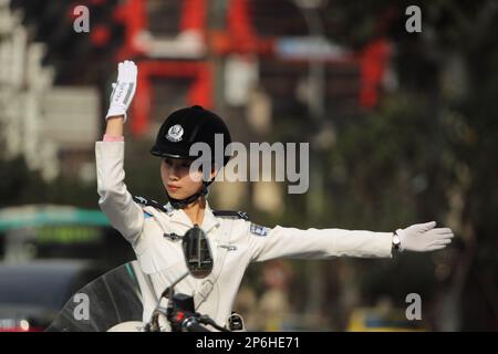 A traffic policewoman directs vehicles on a road in southwest China's ...