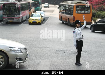 A traffic policewoman directs vehicles on a road in southwest China's ...
