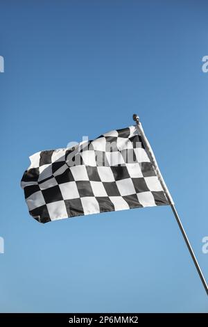 Checkered finish flag on light blue background Stock Photo - Alamy