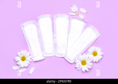Composition with menstrual pads and chamomile flowers on lilac ...