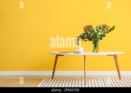 Vase with bouquet of alstroemeria flowers and magazine on table near ...
