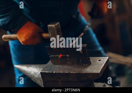 Blacksmith forges and making arrow arrowhead metal detail with hammer ...