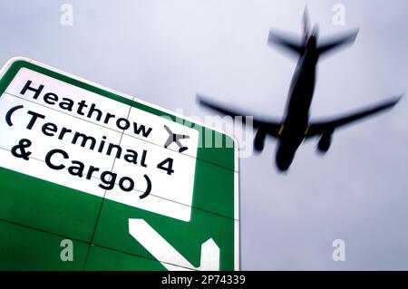 An aeroplane flying above road signs near Heathrow International ...