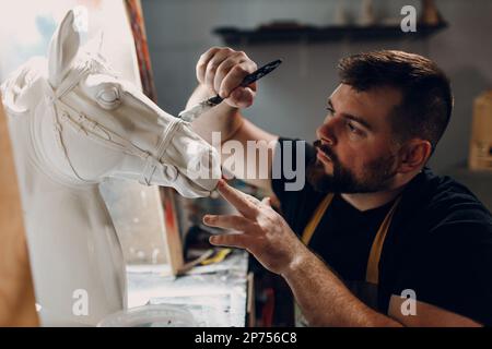 Artisan craftsman create horse based on plaster cast. Gypsum mold and ...