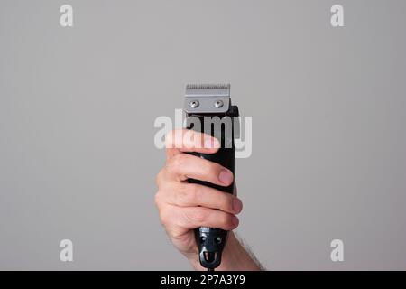 Electric hair trimmer held in hand by Caucasian male hand close up shot ...