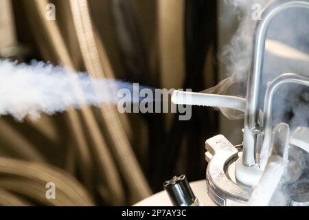 Liquid nitrogen gas emanating from pressurized tank connected to metal ...