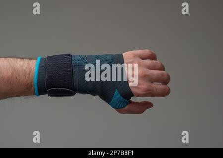 Velcro wrist stabilizer cast worn by Caucasian male hand. A blue split ...