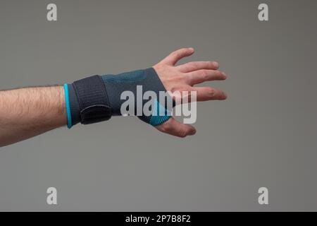 Velcro wrist stabilizer cast worn by Caucasian male hand. A blue split ...