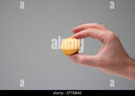 man hold yummy macaroon isolated on blue, copy space. man hold yummy ...