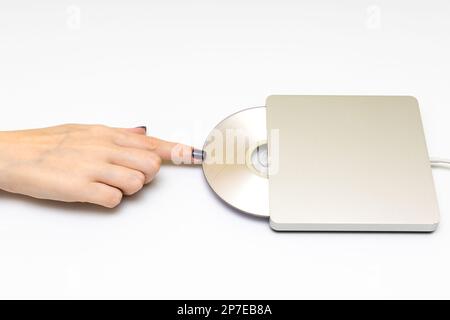 woman inserting a laser disc into a disk drive. the hand takes the disk ...
