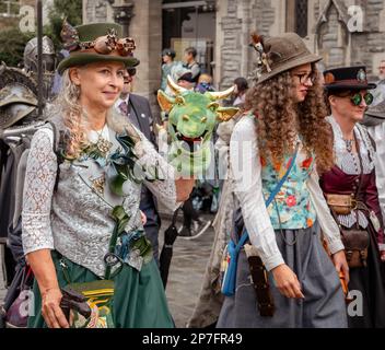 A group of steampunks walking along a street. A male steampunk with a ...