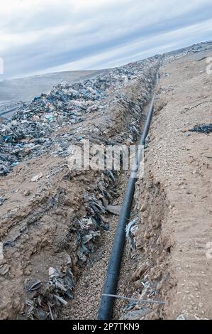 A perforated pipe for methane gas is laid in a trench to be buried in ...