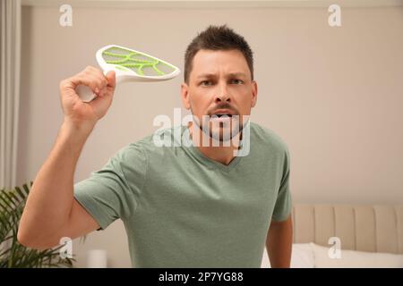 Man with electric fly swatter in bedroom. Insect killer Stock Photo - Alamy