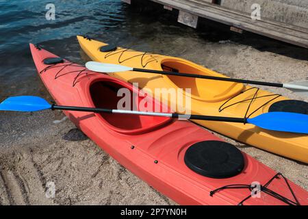 Modern kayaks with paddles on beach near river. Summer camp activity ...